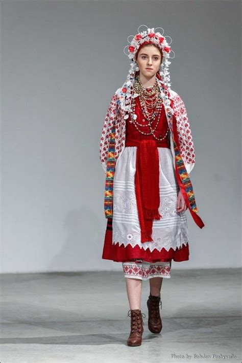 A Woman Is Walking Down The Runway Wearing A Red And White Dress With An Elaborate Headpiece