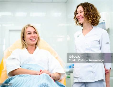 일회용 의료 목욕 가운을 입은 여성이 미용 클리닉에서 상담중입니다 매력적인 여성 의사가 환자와 이야기합니다 뷰티 트리트먼트 기획 마취 의학 개념 가정의 방에 대한 스톡 사진