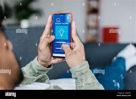 Young Adult Man Using Iot Automation App On Smart Phone Dimming The