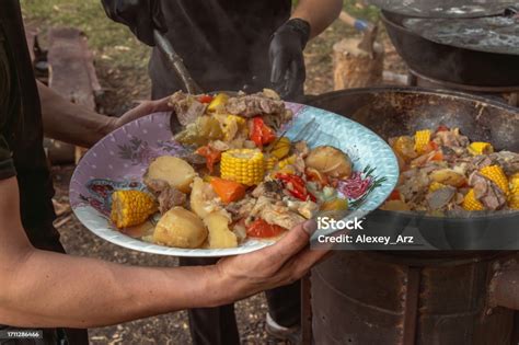 요리사는 주철 가마솥에서 감자와 야채와 함께 튀긴 고기를 접시에 놓습니다 길거리 음식 가마솥에 대한 스톡 사진 및 기타 이미지 가마솥 감자 요리 거리 Istock