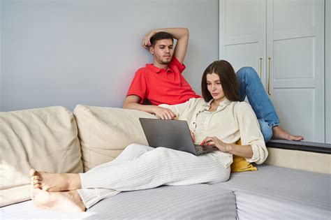 아름다운 젊은 커플 남자와 여자가 소파에 앉아있다 여자는 노트북에서 무언가를보고있다 남자는 그녀 뒤에있다 관계 부드러움 사랑