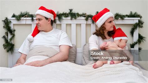 크리스마스와 새해를 위해 장식 된 침대에서 아기와 남편과 아내의 싸움 가정 침실에있는 가족 커플 3 명에 대한 스톡 사진 및 기타 이미지 Istock
