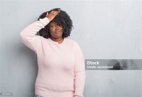 실수에 대 한 머리에 손으로 놀란 젊은 아프리카계 미국인 플러스 크기 여자 겨울 스웨터를 입고 회색 그런 지 벽에 기억 오류 깜