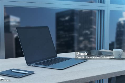 창 배경에서 야간 도시 전망에 노트북과 커피 컵이있는 밝은 나무 테이블에 로고 또는 텍스트를위한 카피 스페이스가있는 빈 어두운 노트북 화면의 원근감보기 3d 렌더링 모의