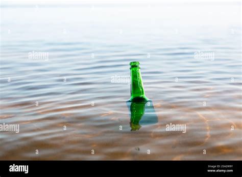 Green Glass Bottle Floating In A River Bottleneck Seen Over Water Surface Environmental