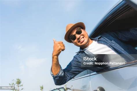 모자를 쓴 여행자가 차를 몰고 차 창 밖으로 몸을 끌어당기고 있습니다 그리고 엄지 손가락이 사진은 자동차로 안전한 여행에 관한 것입니다 차에 대한 스톡 사진 및 기타 이미지