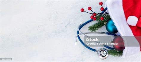 산타 클로스 모자에 크리스마스 트리와 크리스마스 공의 가지와 청진기 배너 흰색 콘크리트 테이블에 모두 개념 메리 크리스마스와 새해 복 많은 새해 또는 건강 한 새해 공간을