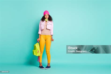 전체 길이 바디 사이즈 사진 의 쾌활 한 긍정적인 귀여운 재미 좋은 예쁜 소녀 착용 캡 모자 배낭 노란색 바지 스트라이프 T 셔츠 고립 위에 선명한 색상 청록색 배경 모자