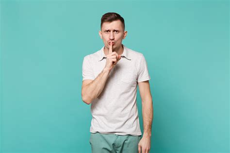 우연한 옷에 젊은 남자가 입술에 손가락으로 조용 하 게 말하는 쉿 제스처는 스튜디오에서 파란색 청록색 벽 배경에 고립 사람들은 진심으로 감정 라이프 스타일 개념입니다 복사