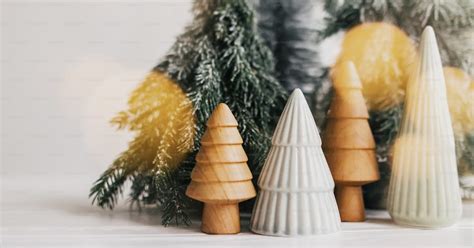 크리스마스 장면 조명에 미니어처 겨울 숲 크리스마스 작은 세라믹 나무와 눈 덮인 소나무가 흰색 배경에 조명을 가지고 있습니다 축제 현대 장식입니다 즐거운 성탄절