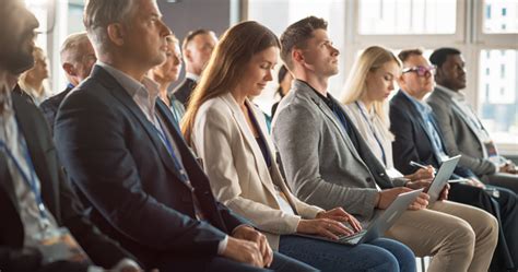 비즈니스 컨퍼런스에서 붐비는 청중 속에 앉아 있는 젊은 여성 노트북에 중요한 글머리 기호를 작성하는 여성 참석자 성공한 사업가들과 함께 강당에서 기조 연설 Launch