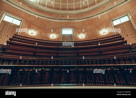 An Interior Shot Of An Old Lecture Hall With Curved Wooden Seating And Iron Railings The Room