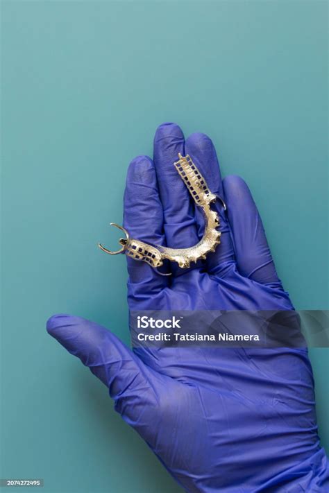 금속 프레임 하부 부분 틀니 코발트 크롬 치과 플레이트 의사의 손에 있는 3d 프린터로 인쇄된 브리지 파란색 배경입니다 플랫 레이 모형 Textvertical의 공간을