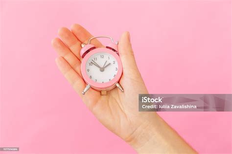 분홍색 파스텔 컬러풀한 트렌디한 배경에 분리된 트윈 벨 알람 시계를 들고 있는 여성 핸드를 디자인하는 심플한 디자인 개념에 대한 스톡 사진 및 기타 이미지 Istock