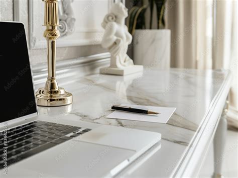 현대 패션 편집자 사무실 노트북과 펜이 있는 흰색 책상 밝은 은색과 베이지색 황동 대리석 늑골 클로즈업 디테일 그리스 조각 액센트 중성 색상 균형과 대칭