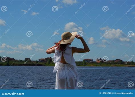 Женщина в белых платье и шляпе очарования на береге реки Стоковое Изображение изображение