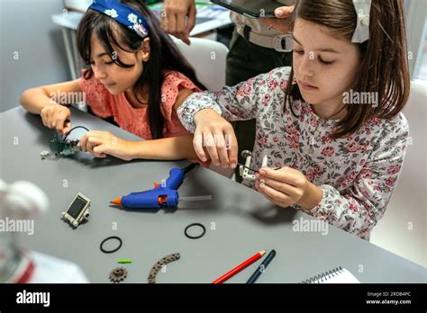 Students Assembling Machine Pieces With Teacher Helping Their In A