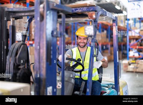 Forklift Truck Operator Lifts Pallet Cardboard Boxes On A Shelf By