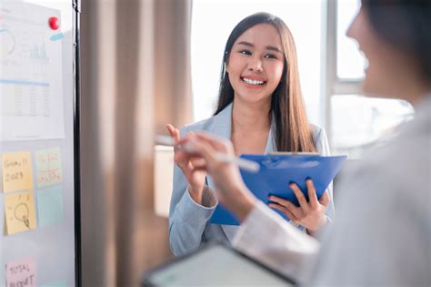 동료와 함께 화이트 보드에서 아이디어를 브레인 스토밍하는 두 명의 사업가 스타트업 회의실에서 재정 예산에 대한 브레인스토밍 세션을 갖는 여성 비즈니스 파트너 25 29세에