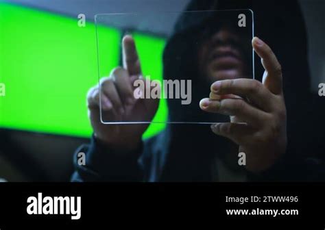 Hacker Using Clear Tablet With Green Screen Monitor Background Stock