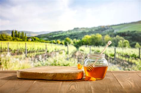 나무 테이블에 꿀의 유리 항아리 와 흐릿한 푸른 나무 와 산 배경 와 자연 배경 와 풍경 와 풍경 음식과 광고 제품을 위한 옥외 배경 그리고 복사 공간 꿀에 대한 스톡 사진