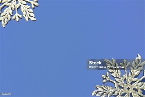 눈송이가 있는 크리스마스 배경 파란색 배경에 반짝이는 두 개의 은백색 눈송이가 배치됩니다 새해 복 많이 받으세요 즐거운 성탄절 엽서 또는 초대장 공간을 복사합니다 플랫 레이