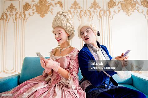 귀족 의상을 입은 우아한 커플이 복고풍 궁전 인테리어에서 현대 기술을 즐기고 있습니다 16 17 살에 대한 스톡 사진 및 기타 이미지 16 17 살 20 24세 2명
