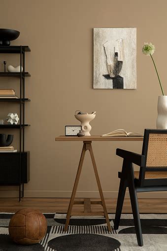 모형 포스터 액자 나무 책상 등나무 의자 검은 램프 책 무늬 카펫 대리석 그릇 및 개인 액세서리가 있는 직장 내부 공간의 아늑한 구성 가정 장식 템플렛 0명에 대한 스톡