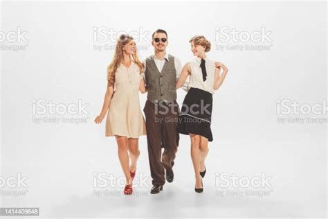 빈티지 옷을 입은 세련된 사람들의 초상화 두 명의 아름다운 여성과 함께 걷는 남자 흰색 배경에 고립 된 포즈를 취합니다 여자에