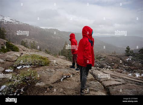 Two Tweens In Red Coats Look Off Into Distance Atop A Mountain Stock