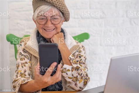 모자와 안경을 쓴 웃고 있는 백인 노인 여성 무선 기술을 사용하는 현대 노인 여성 70 79세에 대한 스톡 사진 및 기타 이미지 70 79세 건강한 생활방식 노인