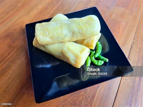 맛있는 룸피아 또는 튀긴 스프링롤은 당근 양배추 콩나물 계란과 같은 야채로 채워진 밀가루로 만든 음식입니다 그린 칠리와 함께 제공되는 사각형 접시에 튀긴 스프링롤 스낵 메뉴