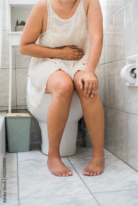 Vertical Image Of A Woman With Diarrhea Sitting On The Toilet In Her Bathroom Stock Photo
