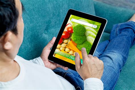 터치 스크린에 온라인 음식을 주문 소파에 누워 태블릿을 들고 남자 손 배달 서비스 음식 쇼핑 개념 온라인 주문 도시에서 라이프 스타일을 가진 비즈니스 및 기술 컴퓨터