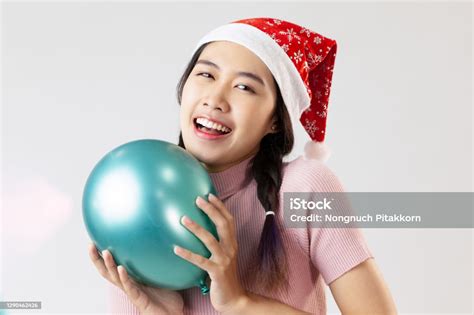 산타 모자를 쓰고 녹색 풍선을 들고 흰색 배경에 미소 짓는 아시아 여성 12월에 대한 스톡 사진 및 기타 이미지 12월 20 24세 가리키기 Istock