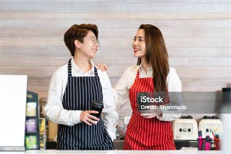 앞치마를 입고 커피 컵을 들고 커피숍에서 카운터 뒤에 서 있는 아시아 여성 부부 젊은 레즈비언 커플 실행 A 카페 함께 2명에