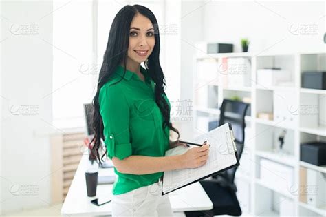 办公室里一个年轻的女孩拿着一支铅笔和一张笔记纸。素材 花瓣网