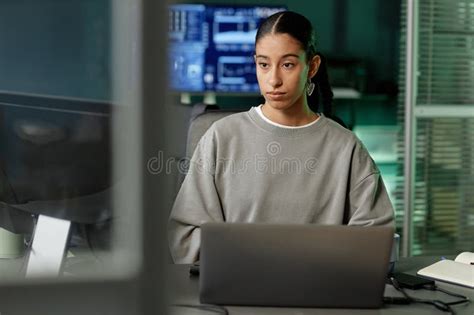 Female It Developer Using Laptop At Working Desk With Computers In