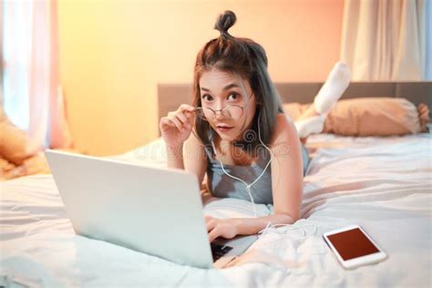 Beautiful And Woman Using Laptop Computer And Listening To Music From Cell Phone On Bed Stock