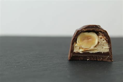 프랄린 화이트 필링과 헤이즐넛 헤이즐넛을 곁들인 초콜릿 사탕 디저트 사탕은 복사 공간 텍스트에 대한 공간이검은 검은 색 배경에 놓여있다 초콜릿의 날 초콜릿 케이스 캔디