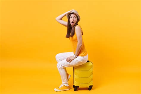 여행자 관광 여자 여름 캐주얼 옷 모자 가방 노란색 오렌지 배경에 고립에 앉아 여성 승객 주말도 주에 여행을 해외 여행 공기 비행 여행 개념입니다 Unmanned