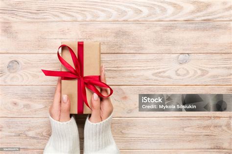 여자 손에 빨간 리본으로 종이에 포장된 발렌타인 또는 다른 휴일 수 제 선물을 제공합니다 선물 상자 흰색 나무 테이블 복사 공간 평면도에 선물의 장식 Diy에 대한 스톡