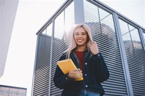 화창한 도시 환경에서 산책 하는 트렌디 한 데님 의류를 입고 화려한 긍정적인 여자 학생의 절반 길이 초상화 귀여운 쾌활한 힙스터 소녀 보고 에 카메라 시 여름 산책 에 거리