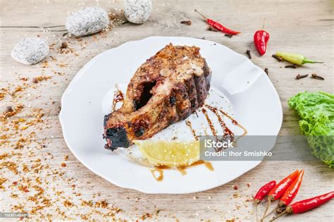 밝은 나무 테이블에 허브와 향신료와 흰 접시에 구운 생선 스테이크에서 보기를 닫습니다 메뉴 또는 조리법에 대 한 해산물 텍스트의