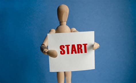 파란색 배경에 있는 나무 남자는 시작이라는 단어가 있는 흰색 종이를 들고 있으며 글자의 내용은 비즈니스 컨셉과 마케팅에 영향을