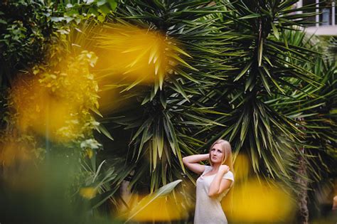 아름 다운 젊은 날씬한 긴 머리 금발 소녀에 흰색 긴 드레스 여 자가 야자수와 자연을 배경으로 포즈를 합니다 터키 세련 된 모델 패션 닫 다 건강한 생활방식에 대한 스톡