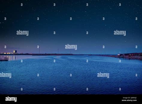 Wind Turbines Stand In The Water Of The Sea Under A Night Sky With