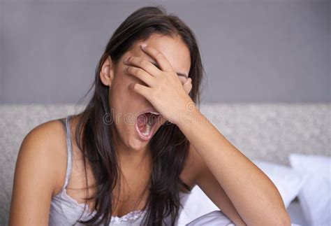 Can I Go Back To Bed Yet A Young Woman Sitting On A Bed Yawning Stock