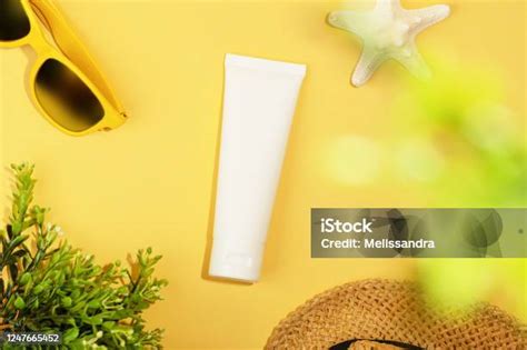 선글라스 불가사리 밀짚 모자 녹색 식물이 있는 여름 배경 노란색 배경에 고립 된 중앙에 브랜드가없는 튜브의 최고 보기 자외선 차단제 크림 세럼용 용기 유기농 화장품 메이크업