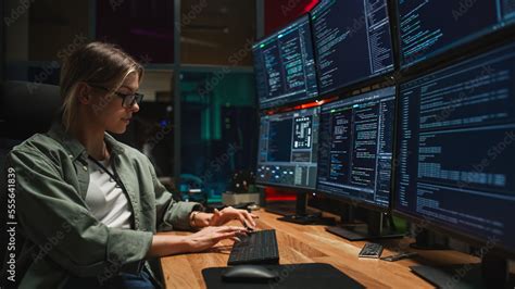 Female Programmer Coding On Desktop Computer With Six Monitors Setup In Dark Office Smart